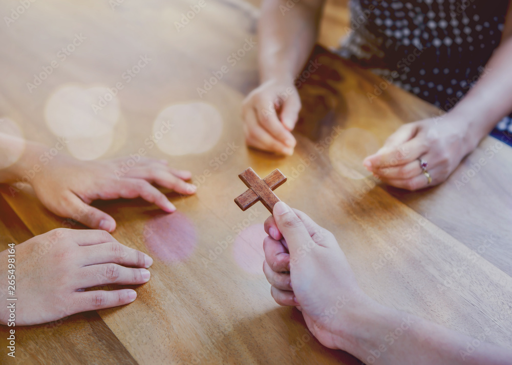 Close up of Young christian man holding small wooden cross in hands ...