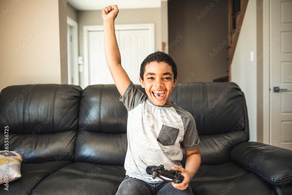Young boy playing video game, at home. Stock Photo | Adobe Stock