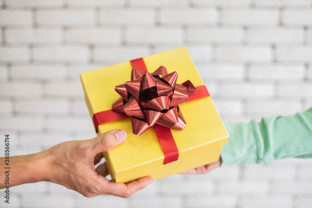 Two people hands handing a box of present to each other in front of ...