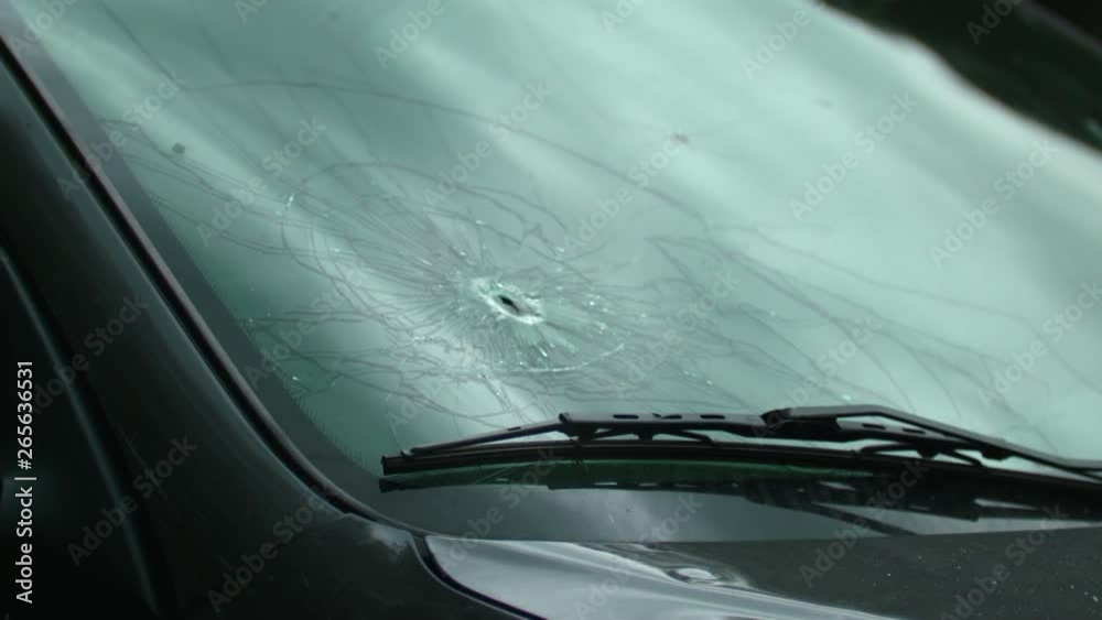 Sniper shoots through the windshield of the car. Fully equipped sniper ...