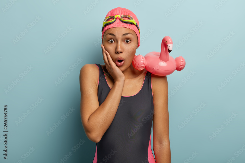 Shocked dark skinned female touches cheek, looks surprisingly, being in ...