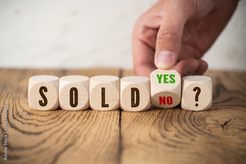 Hand flipping a cube with the answer to the question "Sold?" foto de ...