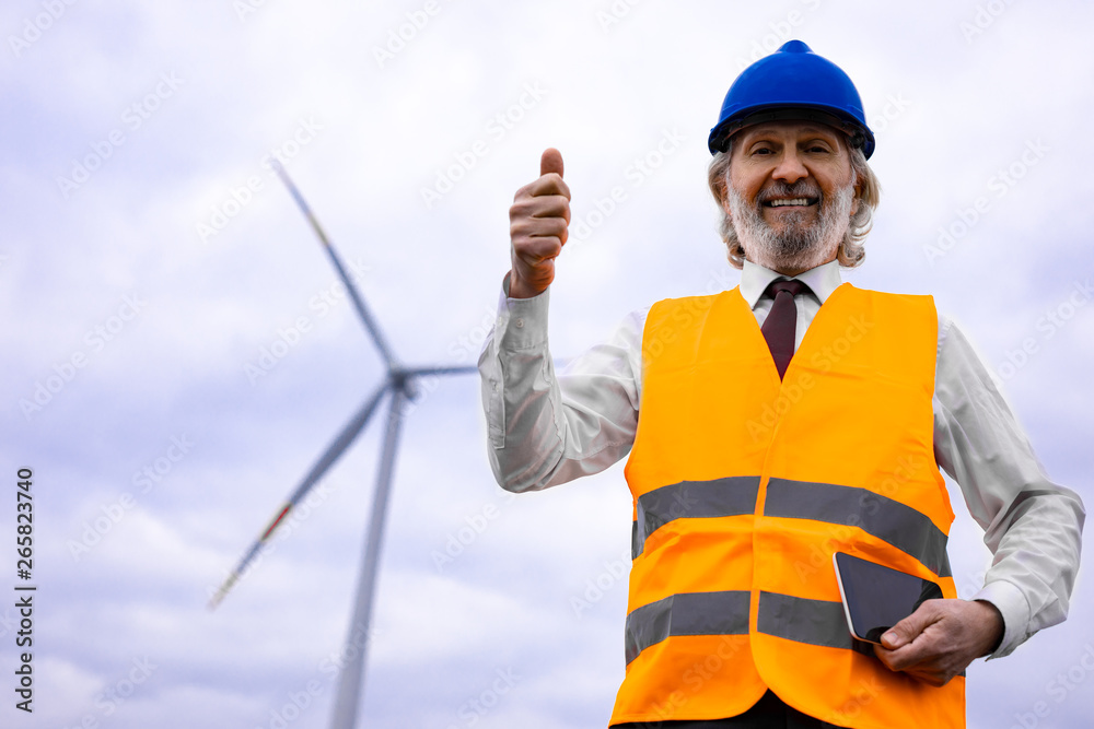 Senior wind turbine engineer showing thumb up in front of the wind ...