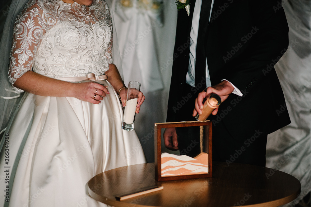 Wedding ceremony, mixing sands is a new family. Close up view hands of ...
