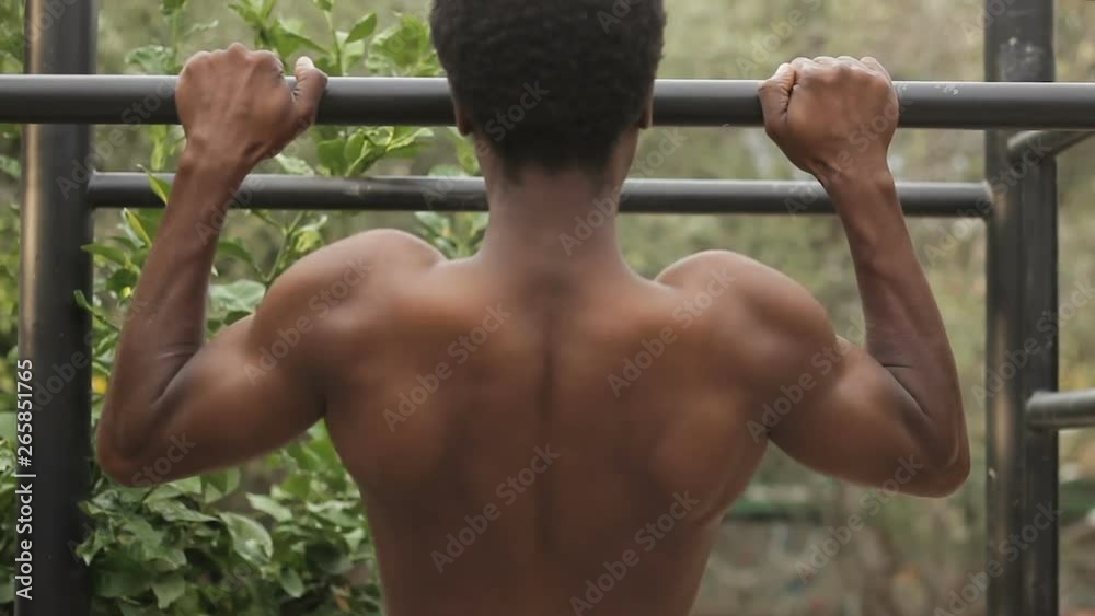 Poor african guy making gym outdoors. muscular man pulling up on ...