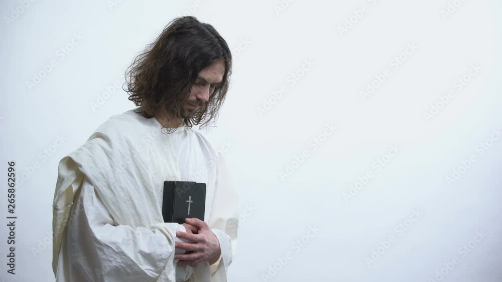 Prophet in white robe holding Bible, praying to God with humility ...