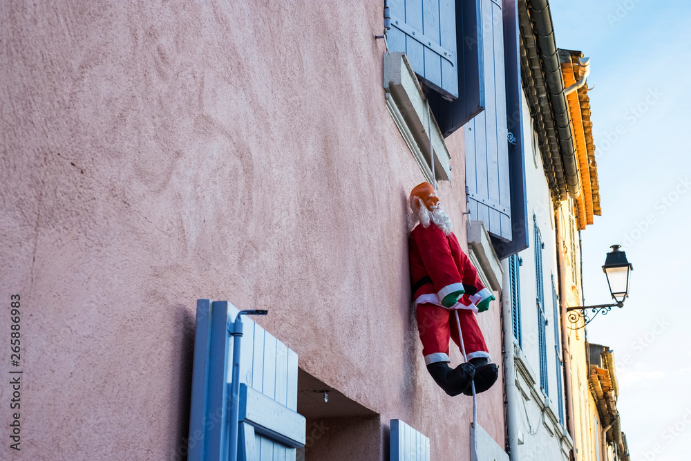 Santa Clause figure hanging on rope from a window of house with pink ...