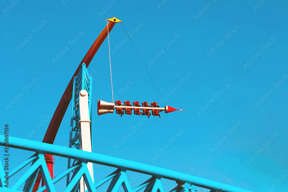 Blue roller coaster people ride on a red rocket ride flies through the ...