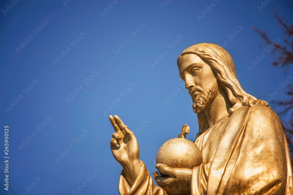 Gold statue Jesus Christ. He holds the sphere with a cross as a symbol ...