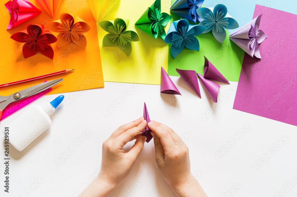 Hands of the girl origami puts flowers from paper of Violet trend color ...
