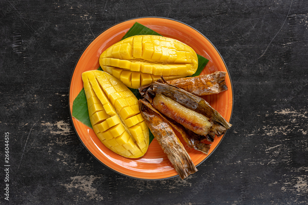 Thai style dessert, yellow mango with banana sticky rice in palm leaves ...