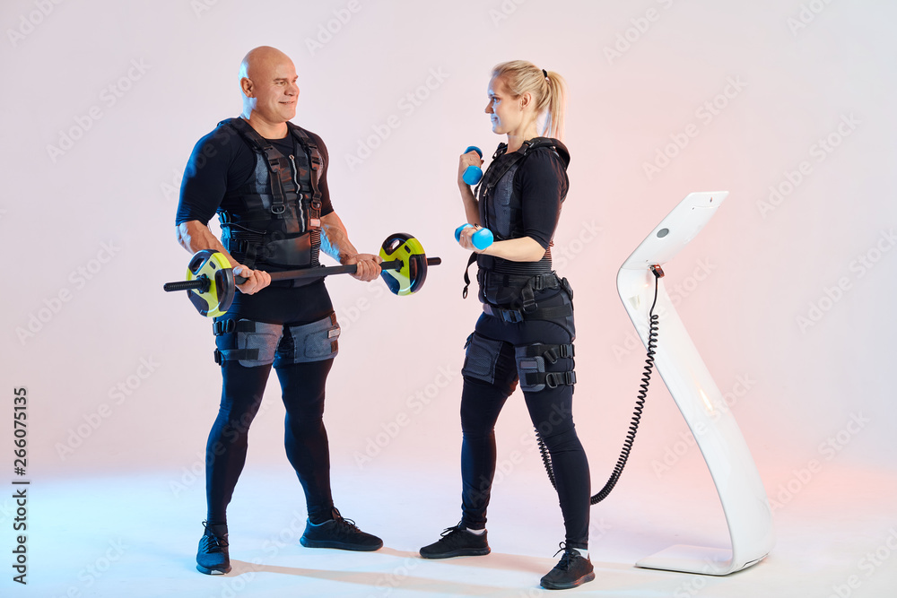 blond woman and man in full electrical muscular stimulation suits doing ...