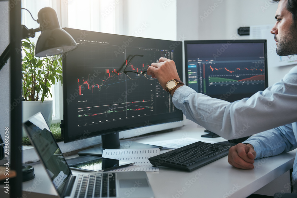 Forex market. Young trader is pointing at graphs on computer screen and ...