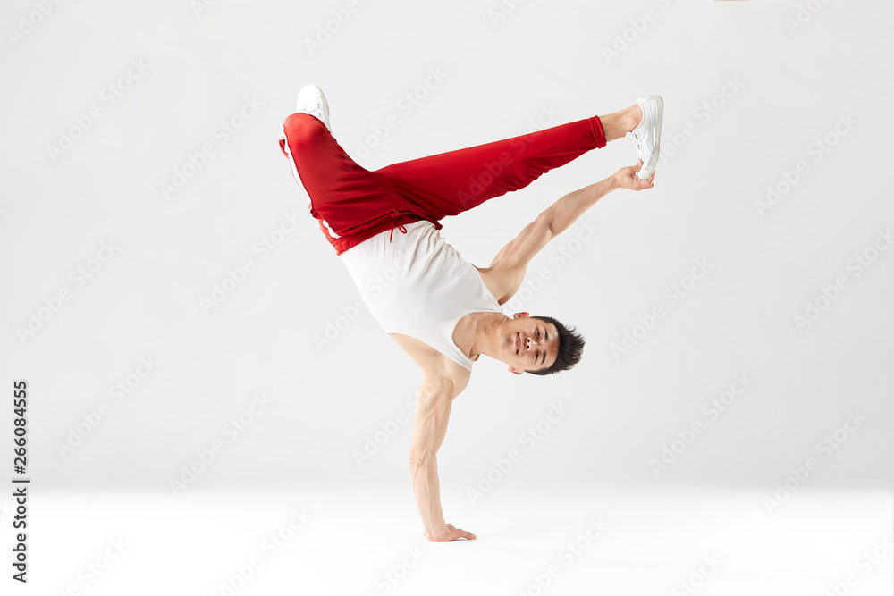 Athletic young b-boy standing on one hand while dancing break dance and ...