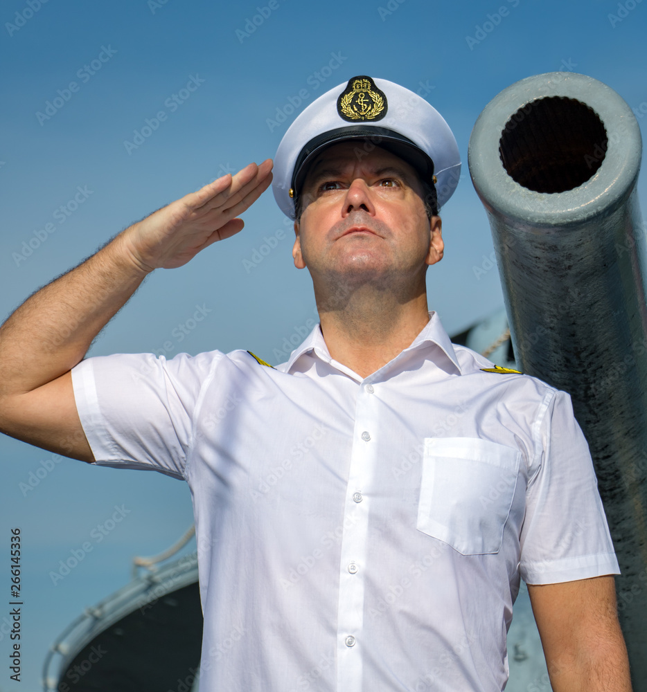 A navy officer standing under a ship's cannon and do salute.The captain ...