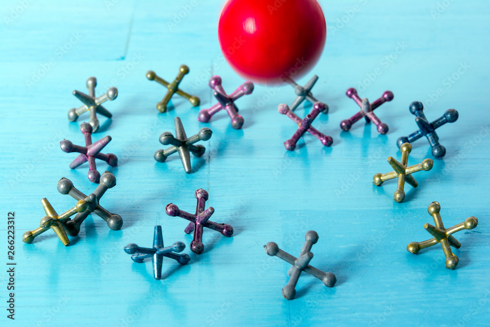 old set of metal jacks on blue wood table with bouncing red rubber ball ...