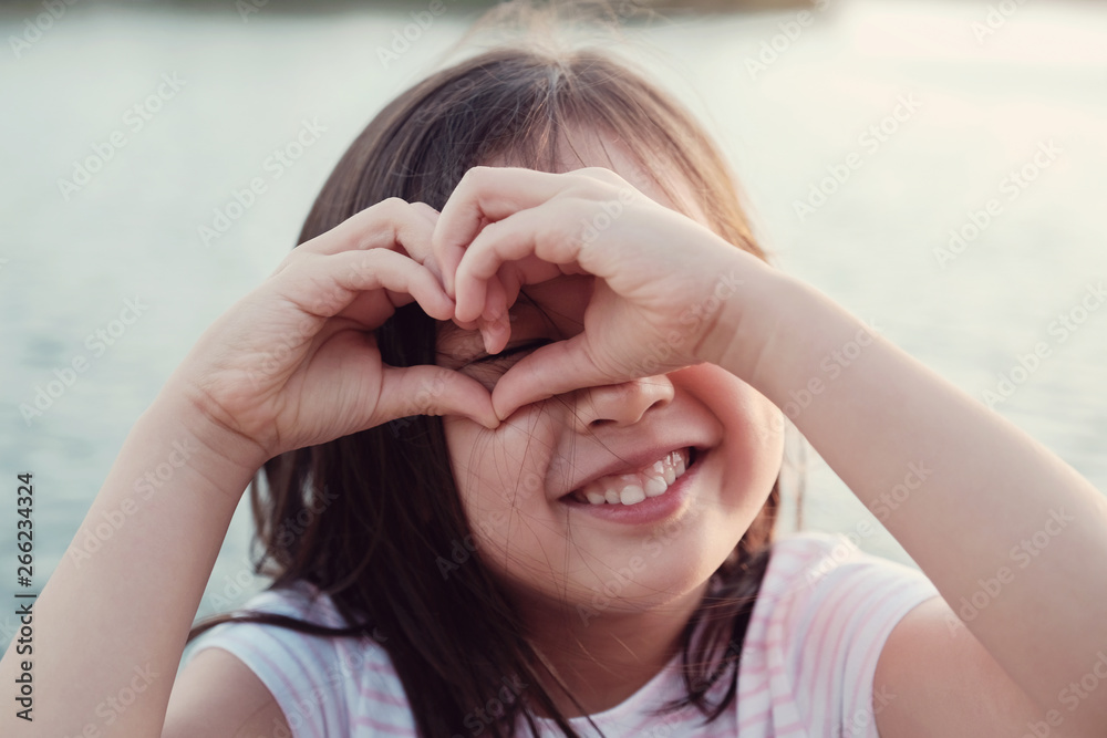 Happy Asian girl making a heart shape with her hands for heart health ...