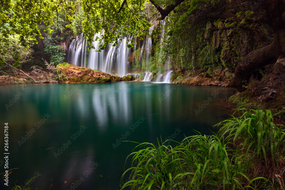 Stunning waterfalls with small emerald lake in deep green forest in ...