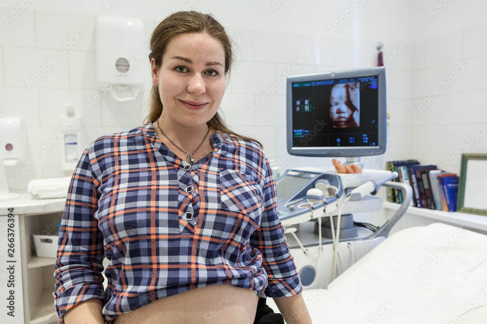 Portrait of pregnant woman in hospital room with 3d model of fetus on ...