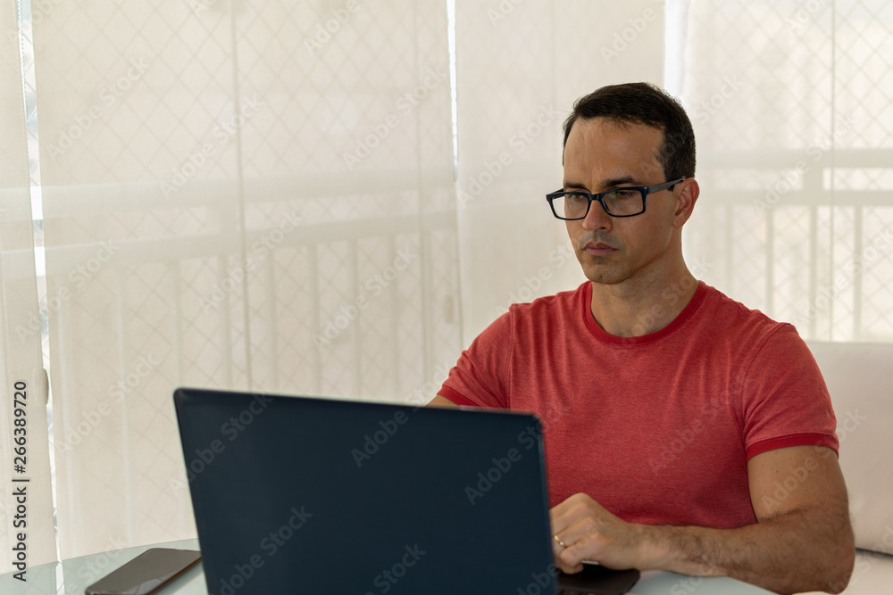 mature man in glasses working at home and messing on his computer ...