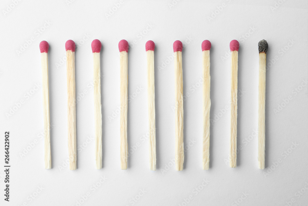 Row of whole matches and burnt one on white background, top view ...