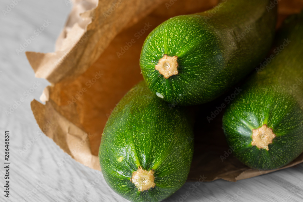 Organic courgette in a brown paper bag on grey wood. Recycle packaging ...