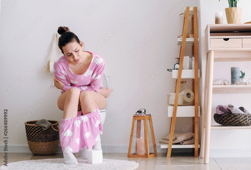 Young Woman Suffering From Diarrhea On Toilet Bowl At Home Stock Photo young-woman-suffering-from-diarrhea-on-toilet-bowl-at-home-stock-photo