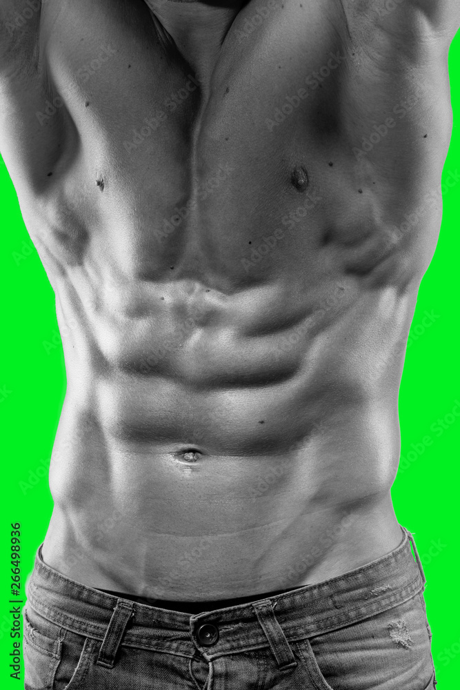 Close up of a strong athletic muscled man in jeans standing on chroma ...