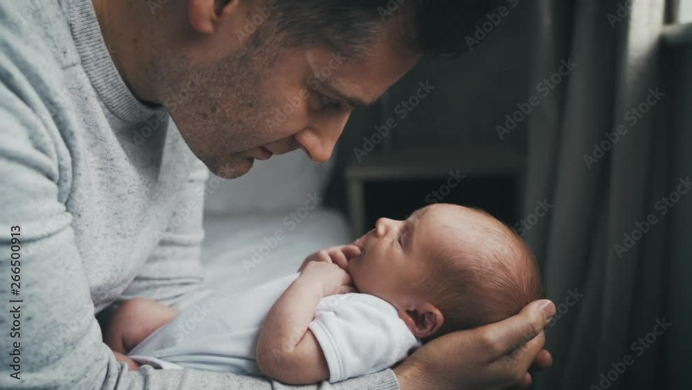 Newborn baby boy in the arms of his father. Daddy and son stare at each ...