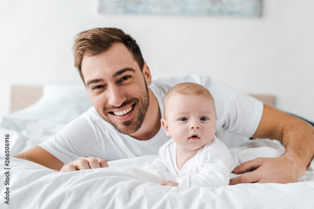 laughing dad lying on bed with cute baby and looking at camera Stock ...