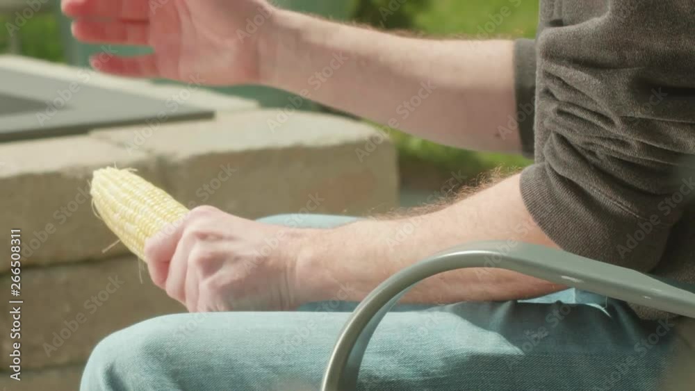 Man Brushing Off Corn on the Cob on Patio TILT UP CLOSE UP SLOW MOTION ...
