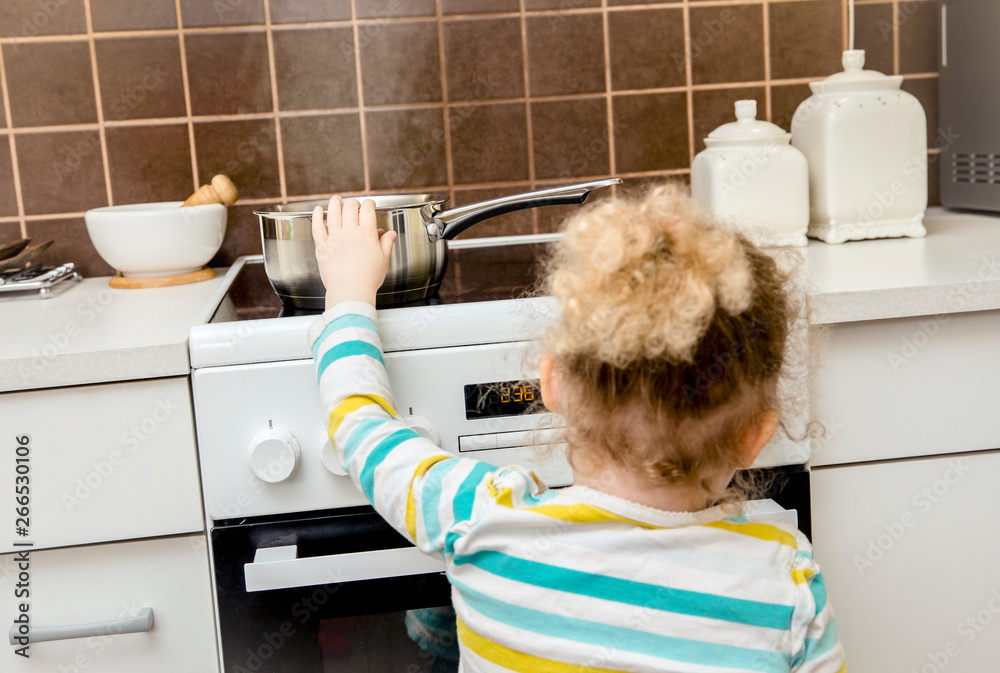 Accident waiting to happen. Toddler girl pulling boiling pot of water ...