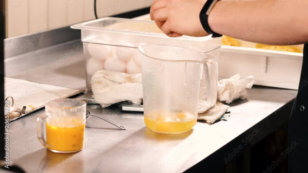 Man Cracks White Eggs Into Measuring Cup In Pro Kitchen. Panning close ...