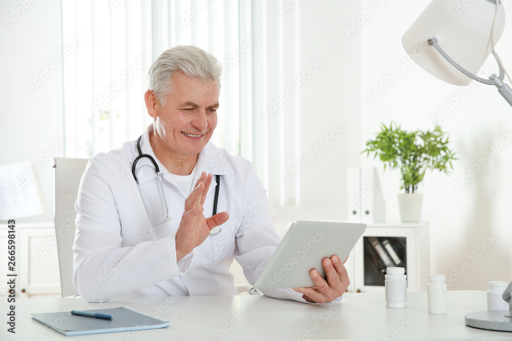 Doctor consulting patient using video chat on tablet in clinic Stock ...