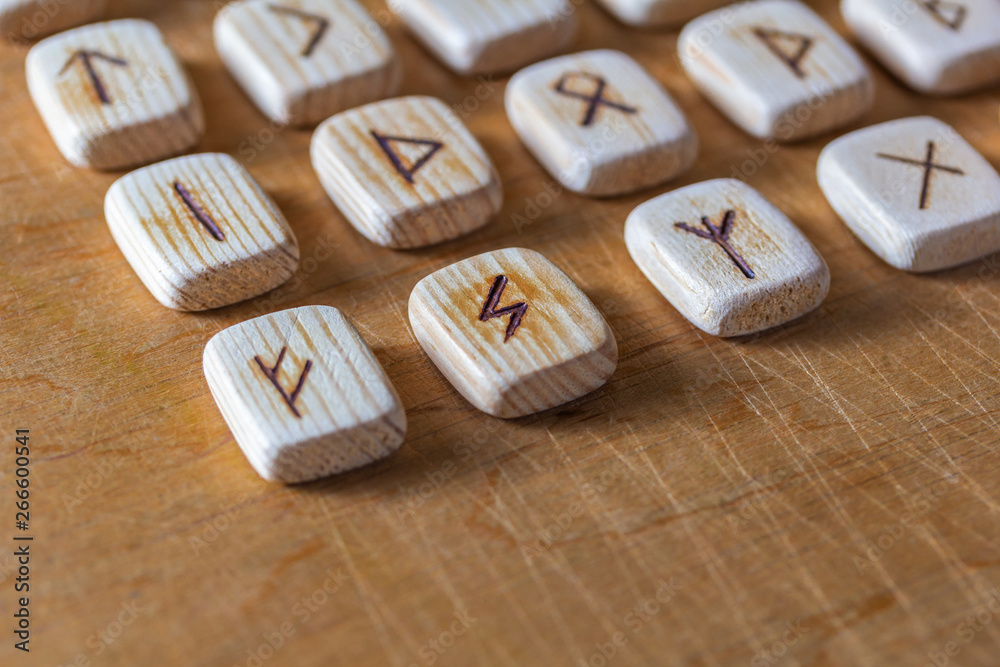 Anglo-saxon wooden handmade runes on the vintage table On each rune ...