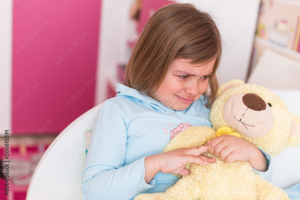Cute adorable little girl crying in children's room hugging teddy bear ...