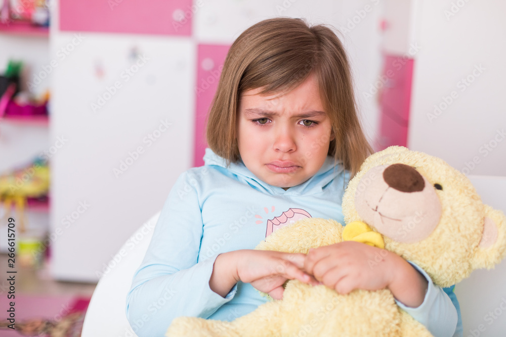 Cute adorable little girl crying in children's room hugging teddy bear ...