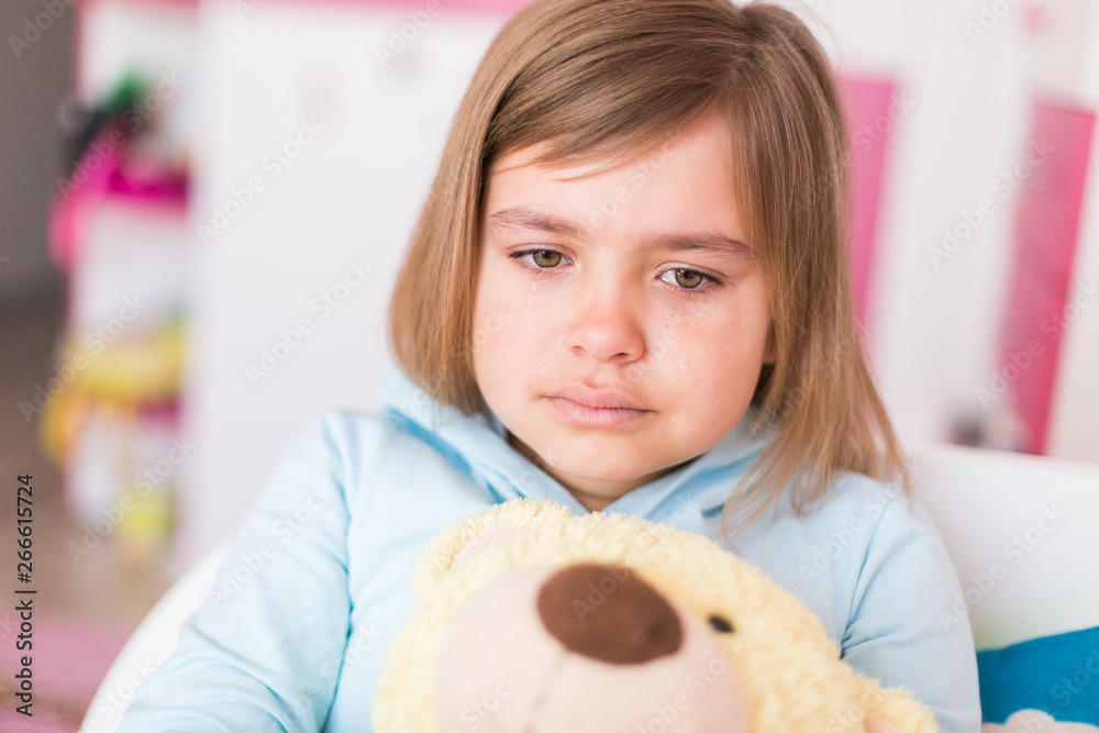 Cute adorable little girl crying in children's room hugging teddy bear ...
