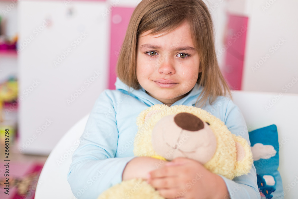 Cute adorable little girl crying in children's room hugging teddy bear ...