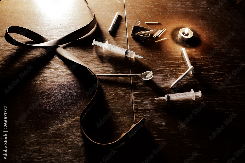 Needle syringe lying on the table. Drugs addict. Candle burning with ...
