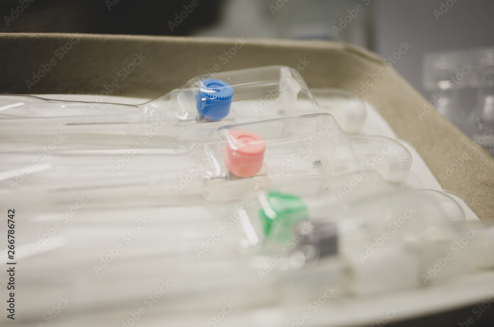 Intravenous cannula of different sizes, colour coded, on a tray in the ...