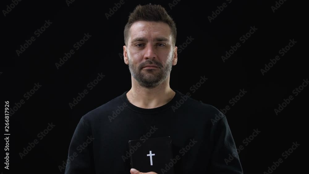 Crying male with bible hands looking camera on dark background, mercy ...