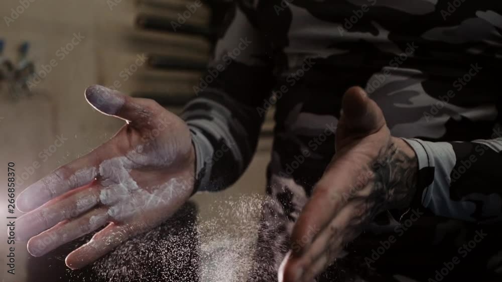 Tattooed muscular hands of a man clapping talcum powder close-up in ...