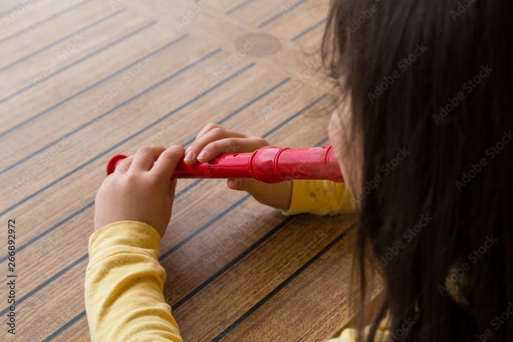 child playing and tuning red flute in a music school for education ...