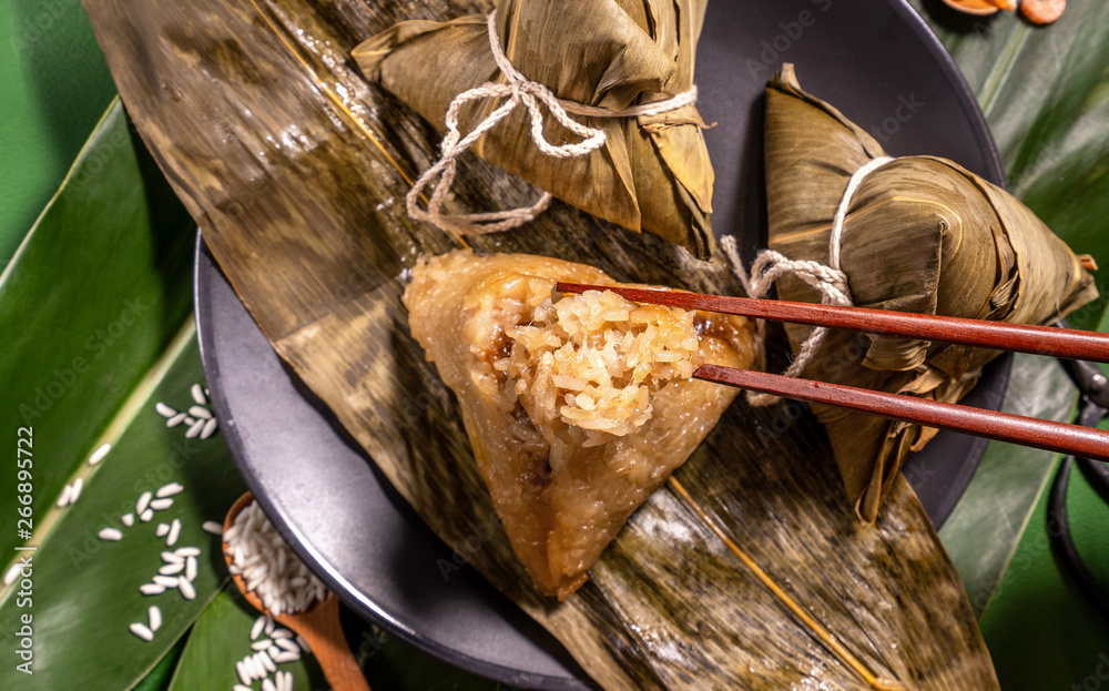 Zongzi, woman eating steamed rice dumplings on green table background ...