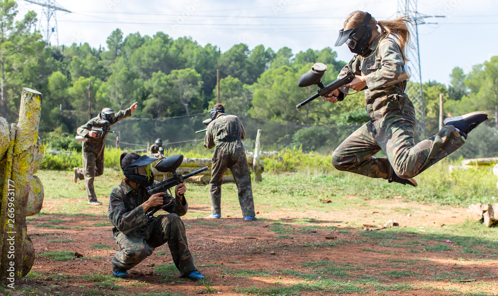 Dynamic paintball battle. Portrait female player jumping and aiming ...
