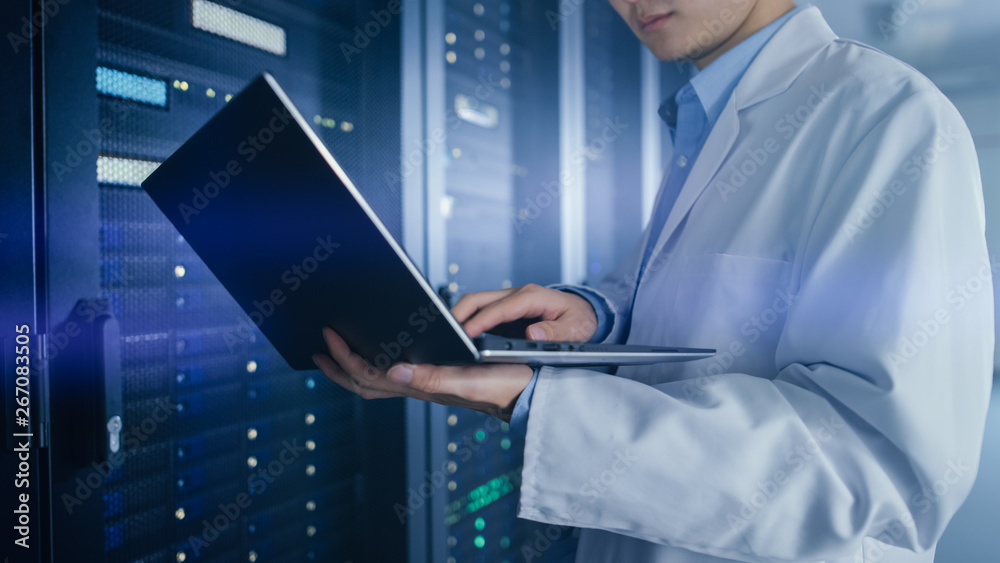 In Data Center: Male IT Specialist Wearing White Coat Stands Beside ...