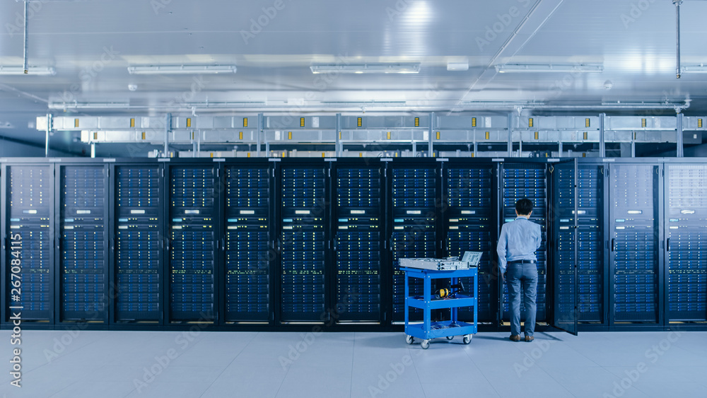 In the Data Center: IT Engineer Working with Server Racks Works with ...