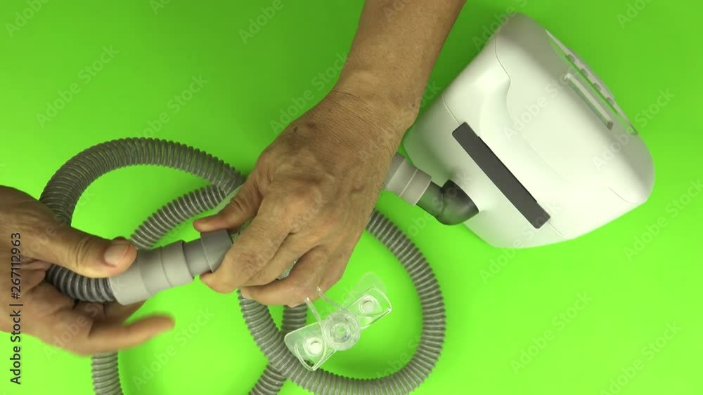 CPAP routine maintenance. Man hands assembling tube to a cpap mask ...