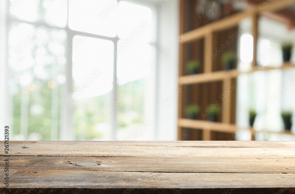 Wood table top on blur of window glass and abstract green from garden ...